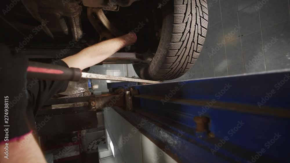 Mechanic stands in the pit and checks suspension at the car service ...