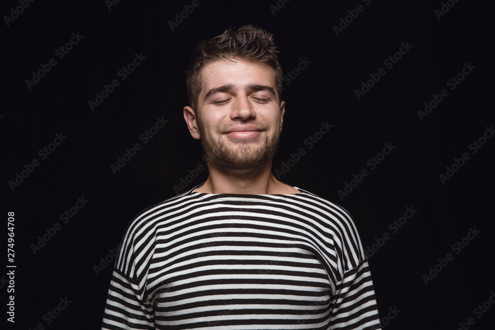 Close up portrait of young man isolated on black studio background ...
