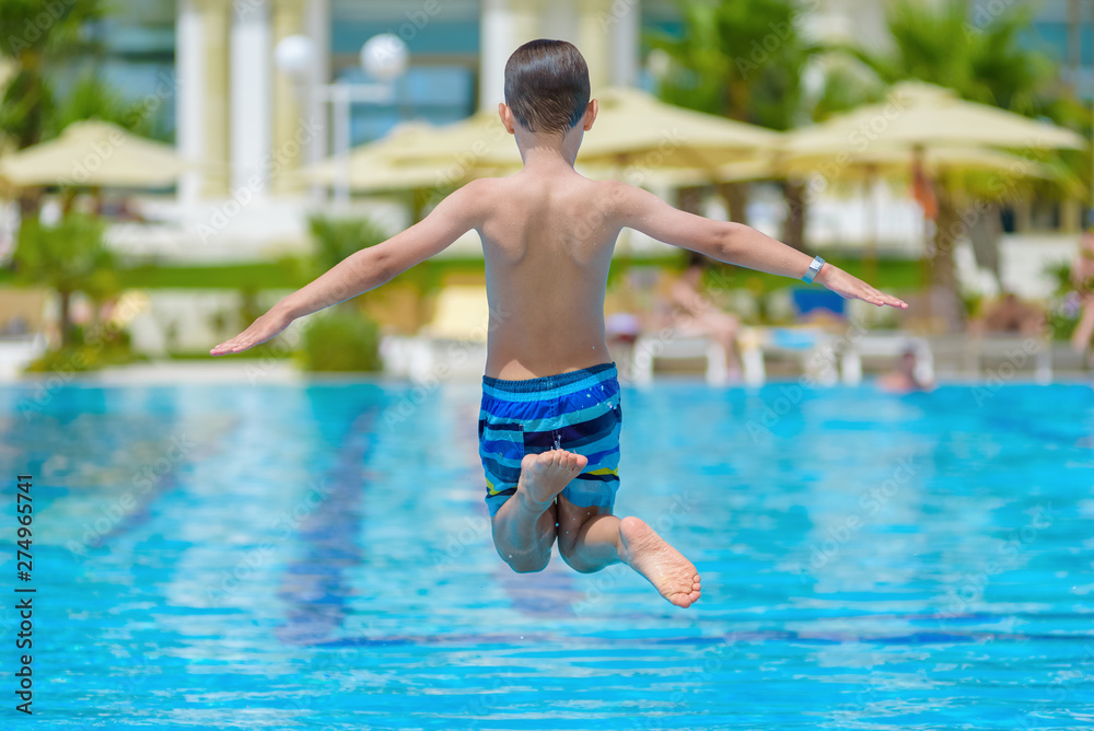 Caucasian boy having fun making fantastic jump into swimming pool at ...