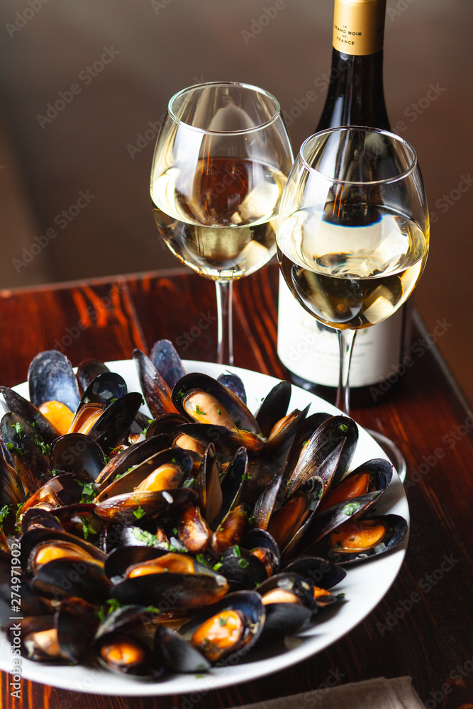 Fine dining in a seafood restaurant: a big dish of mussels with bottle ...