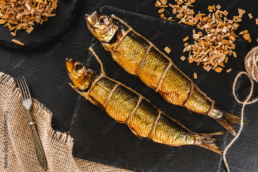 Appetizing smoked fishes with sawdust and burlap texture on slate stone ...