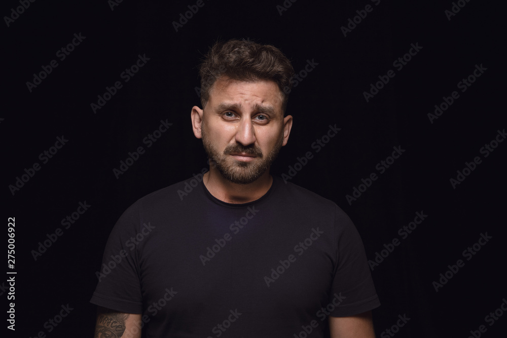Close up portrait of young man isolated on black studio background ...