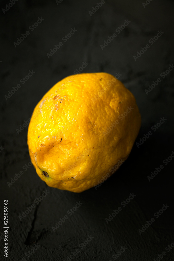 Trendy ugly organic lemon unusual shape close-up on dark background ...