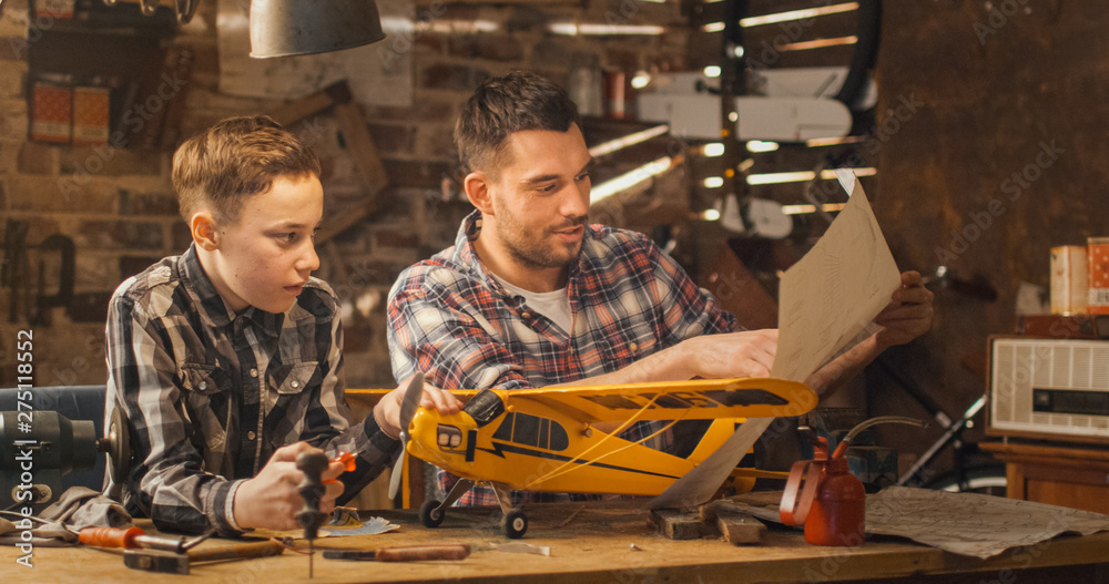 Father and son are modeling a toy airplane in a garage at home. Stock ...