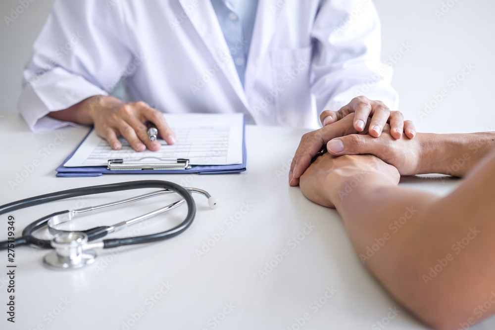 Doctor touching patient hand for encouragement and empathy in the ...