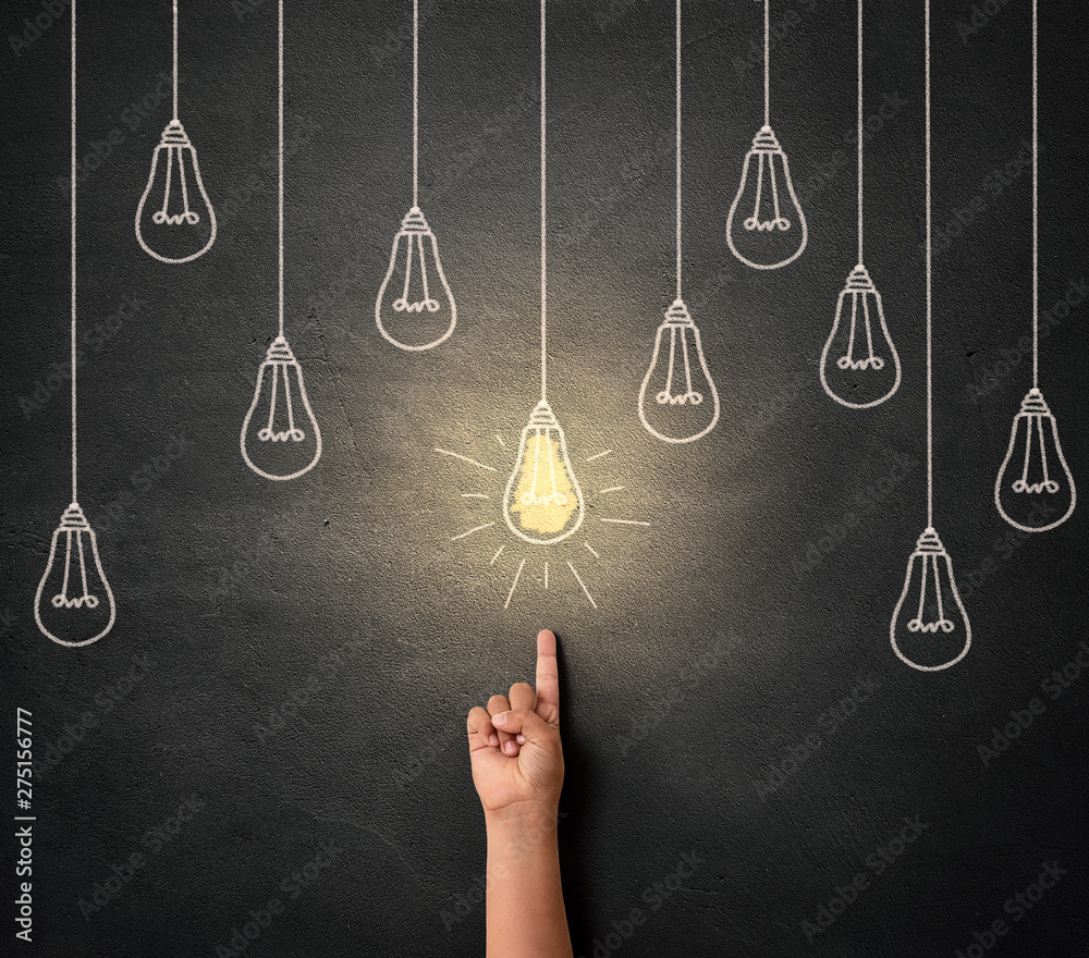 Childs hand pointing at the glowing light bulb drawn on the concrete ...
