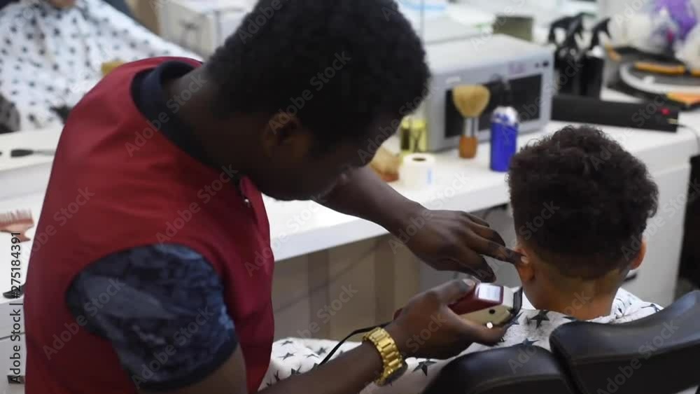 Boy in the african barbershop. Cute mixed boy makes a haircut in the ...
