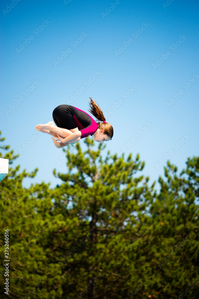 Little caucasian female 8 years old girl jumping in crouching position ...