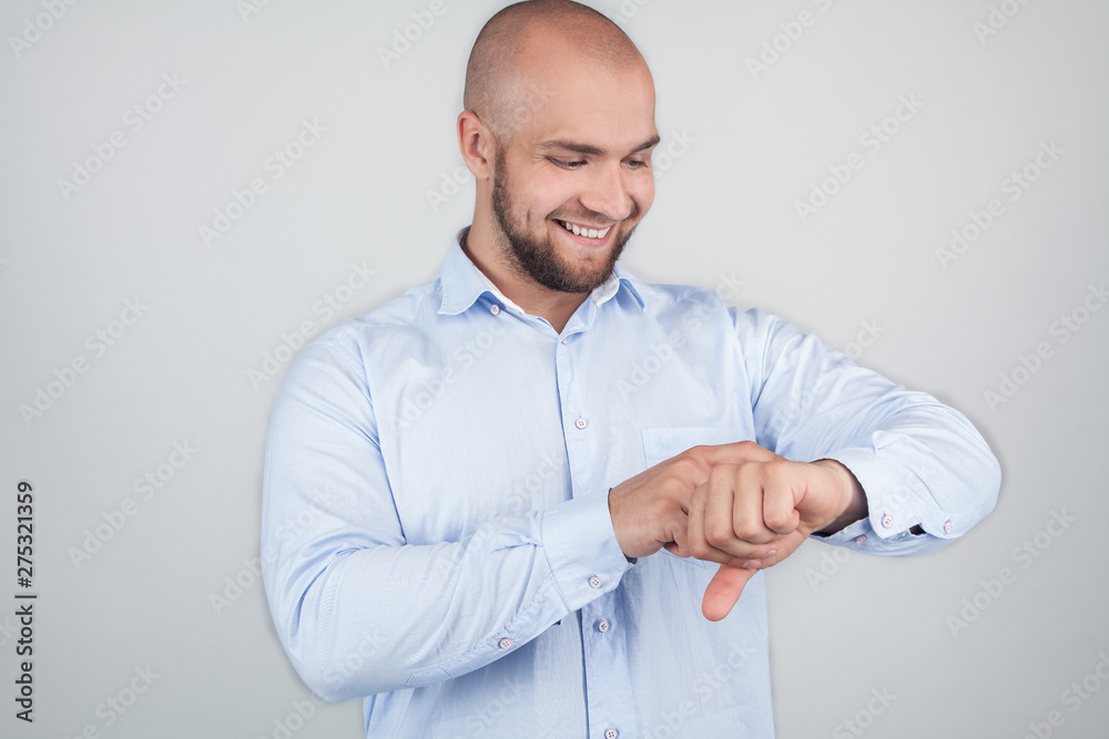 Punctual man points at wrist, being very emotional, wears white shirt ...