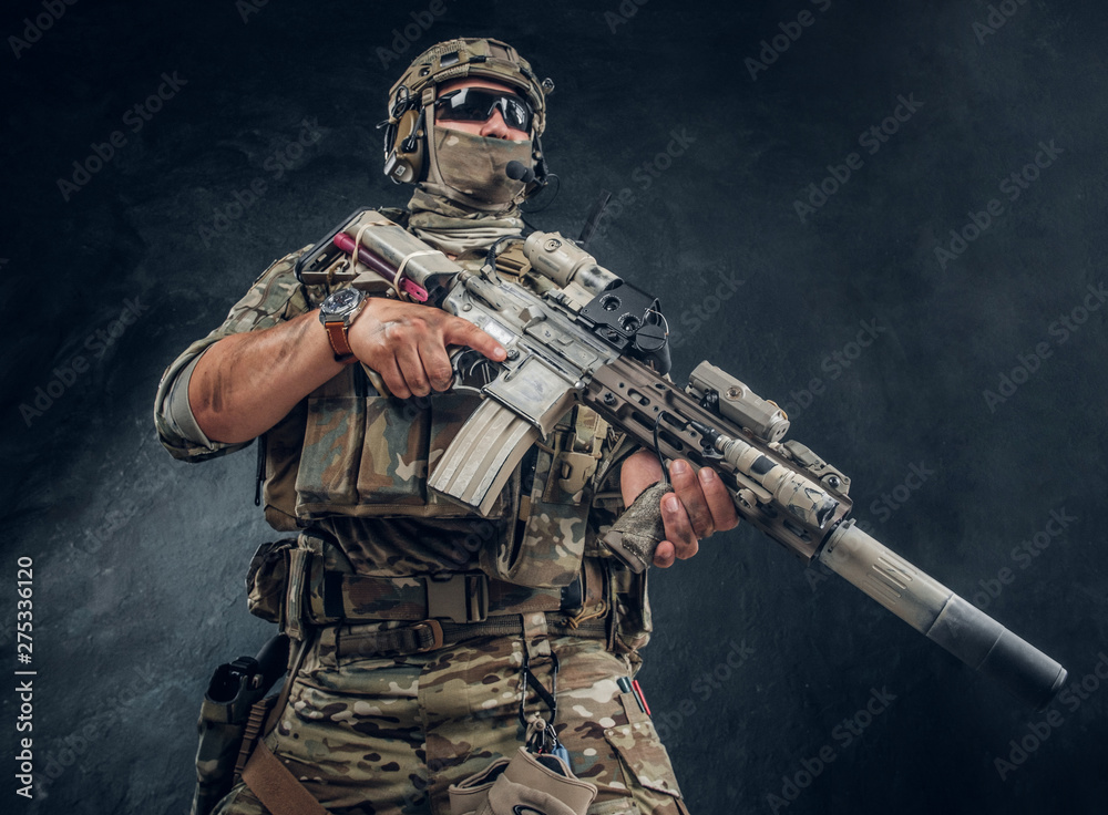 Military man in full equipment with wach on his hand is holding machine ...