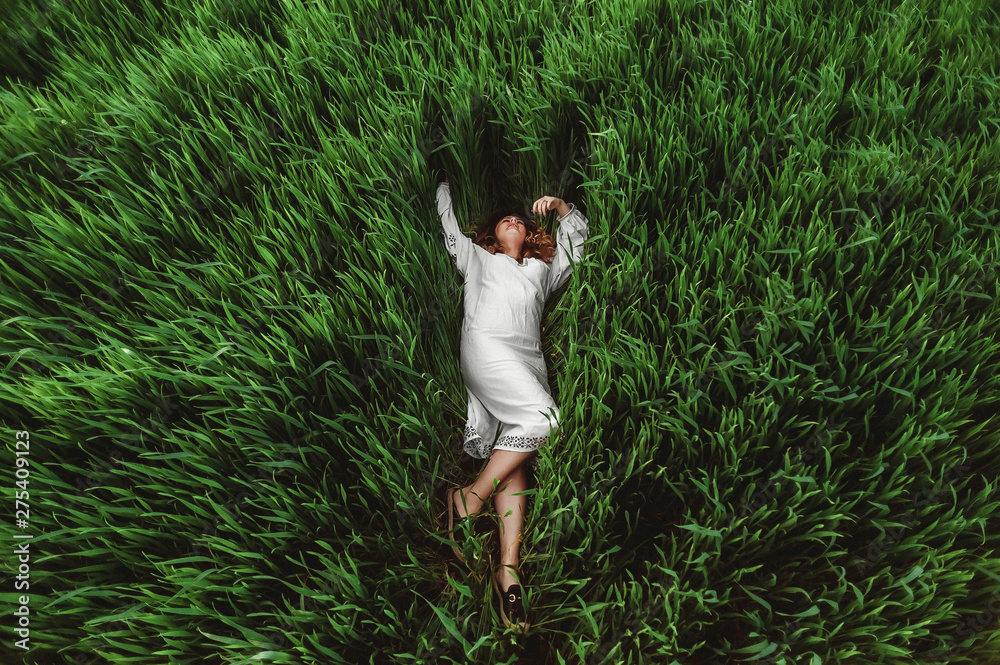 beautiful girl lying on her back; one girl in the field; the girl lies ...