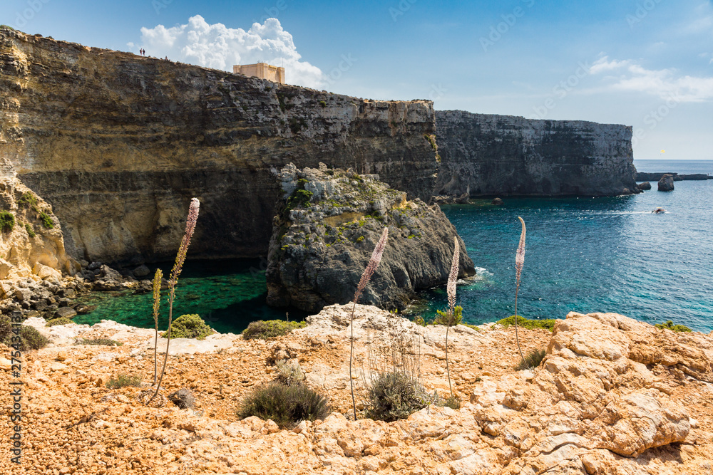Steep coast of Blue Lagoon harbor and on St Maria watchtower on island ...