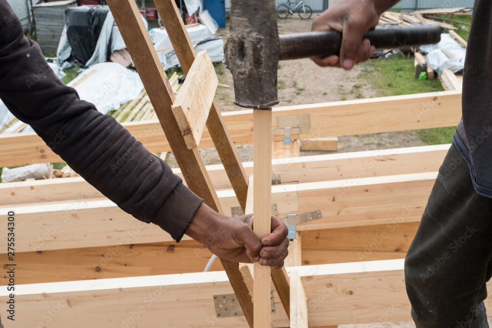 Workers, carpenters, hammering wooden pins with a sledgehammer. Details ...