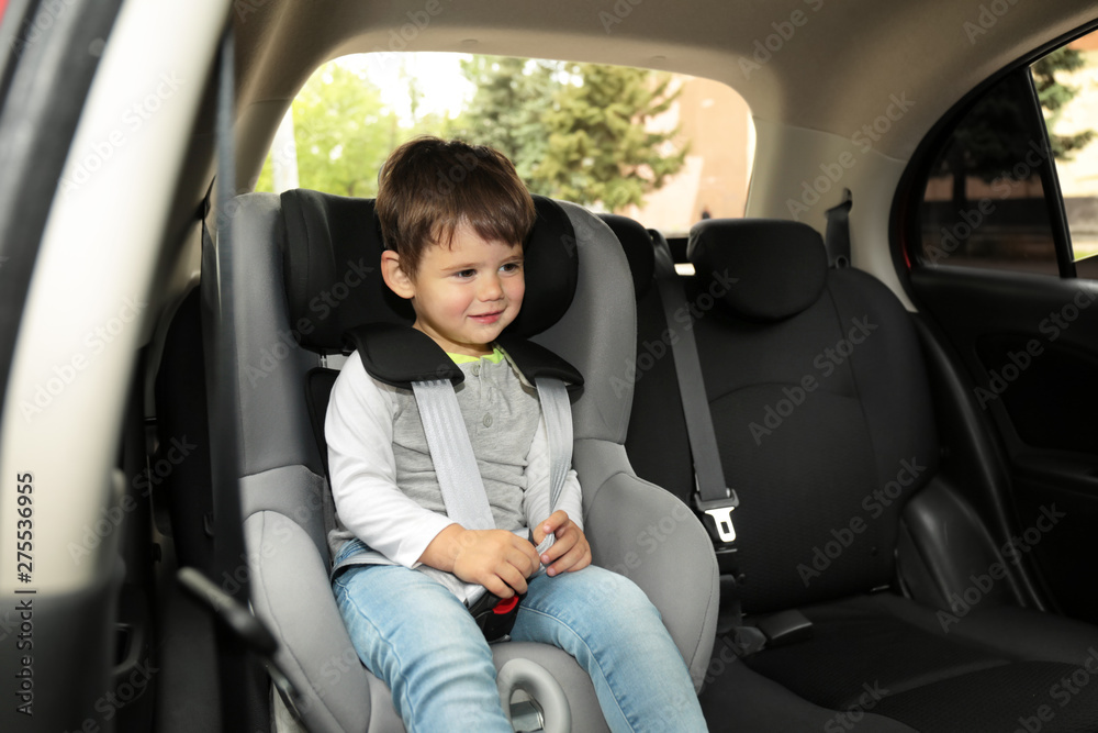 Cute little child sitting in safety seat inside car. Danger prevention ...