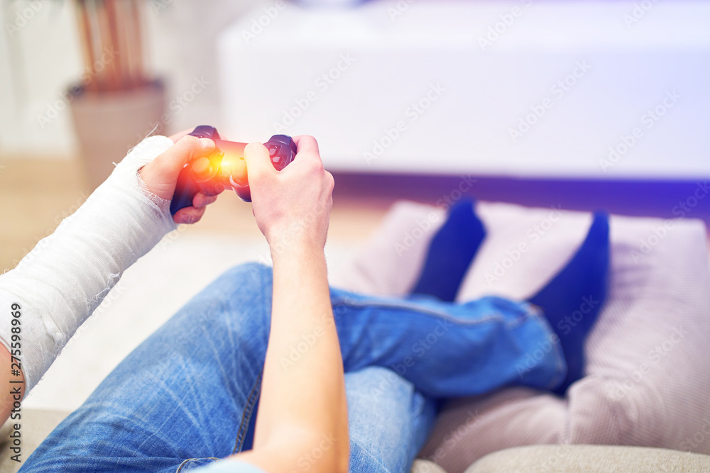 Man with broken arm in plaster cast holding controller and playing in ...