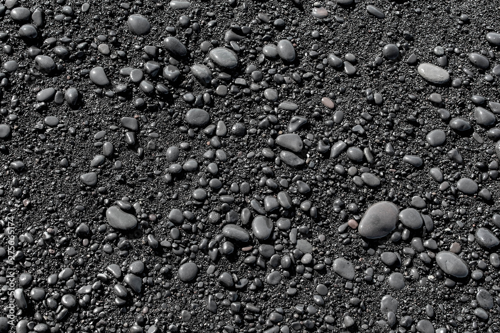 Wet black pebbles from black sand beach of Reynisfjara beach in Iceland ...