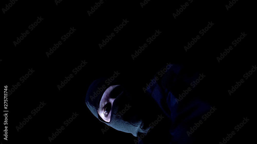 Serial killer in balaclava closing body bag with victim of murder ...