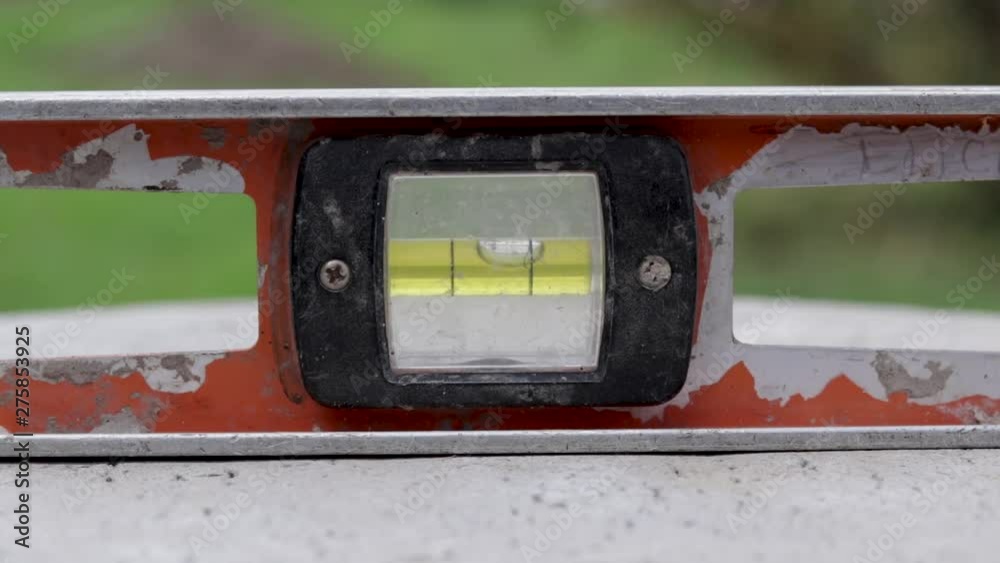 A worker using a level tool for measuring the flatness of the surface ...