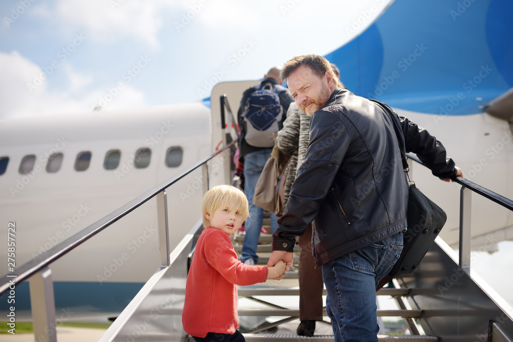 Little boy and his father climb the gangway into the plane against the ...