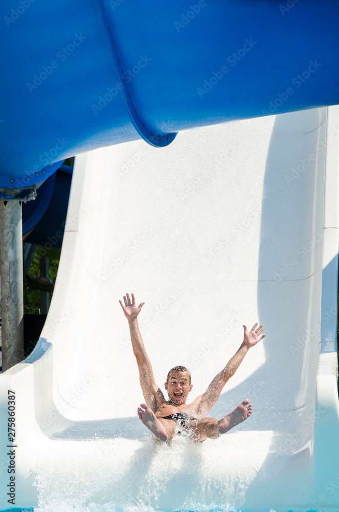 The man rolls down a water slide. In aquapark boy slides down from ...