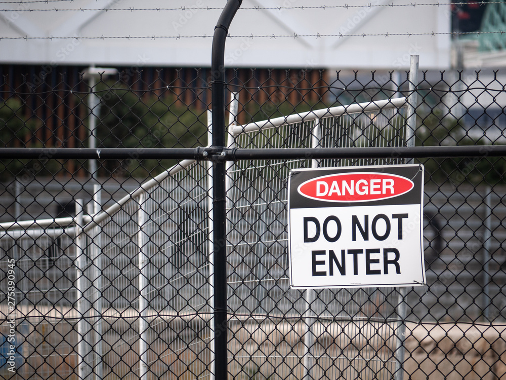 Warning sign of 'Danger Do Not Enter' on galvanised wire security mesh ...