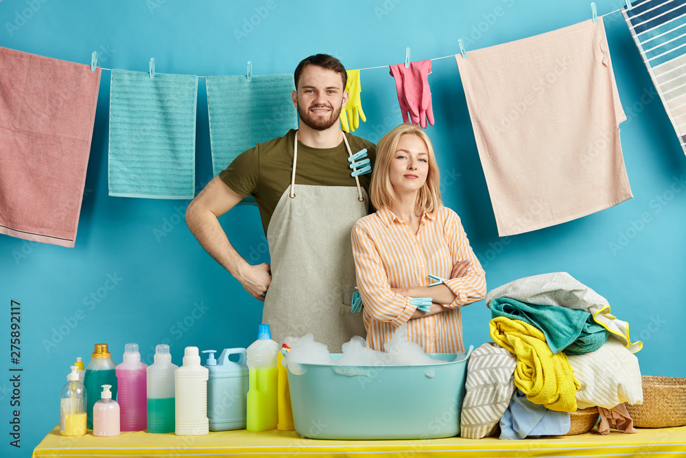 smiling positive hardworking couple ready to help you with laundry ...