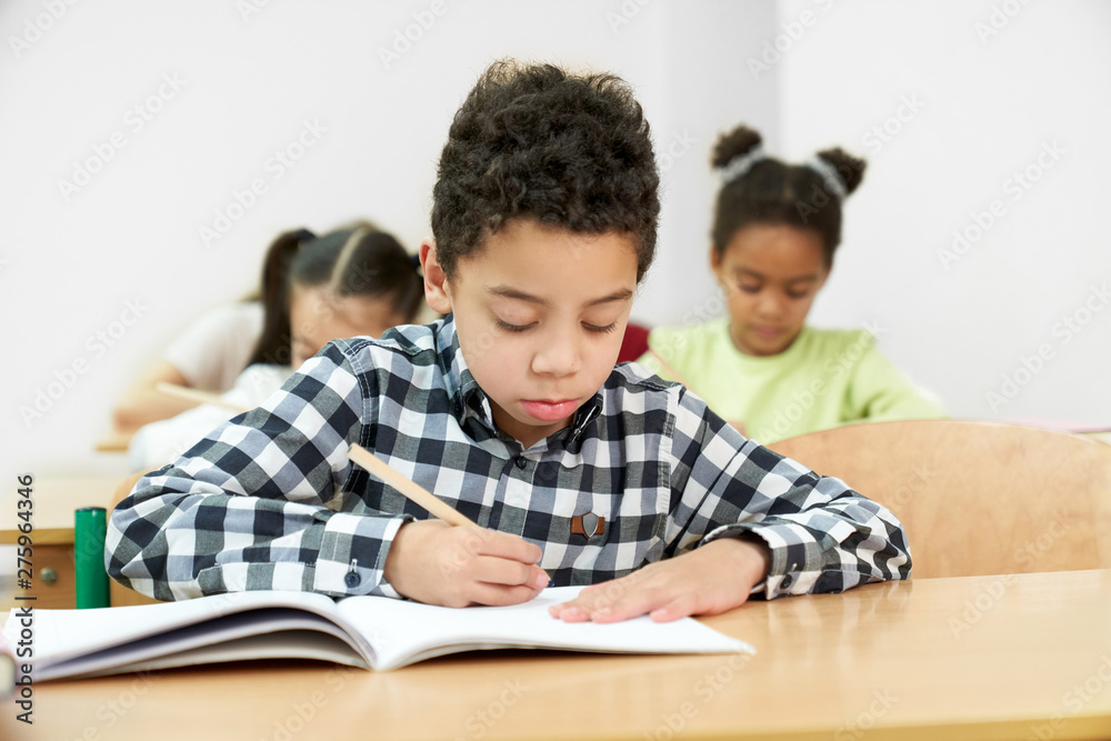 Front view of little boy in process of doing test at school Stock Photo ...