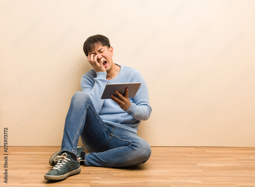 Young chinese man sitting using his tablet desperate and sad Stock ...