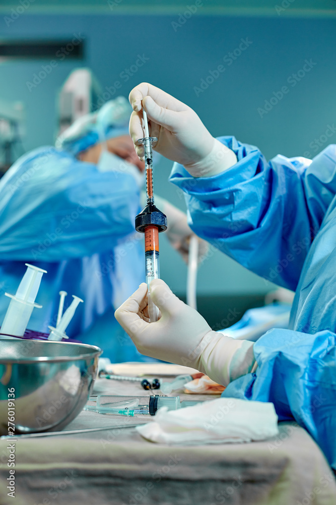 Hands hold syringes to carry fat during work. The operation to transfer ...