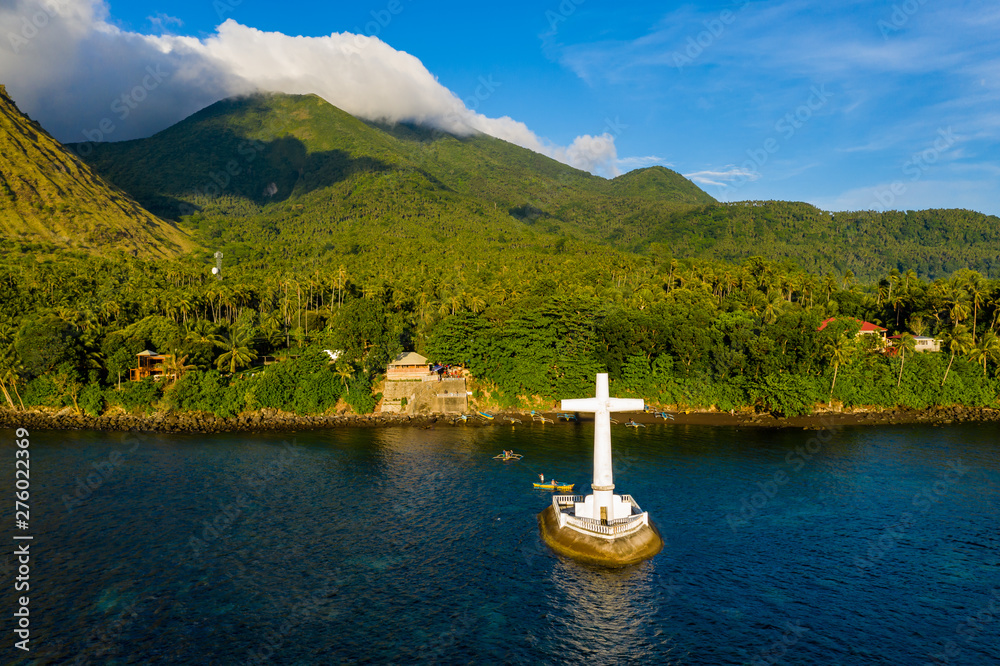 Aerial drone view of a cross in the ocean with steep Mount Vulcan and ...