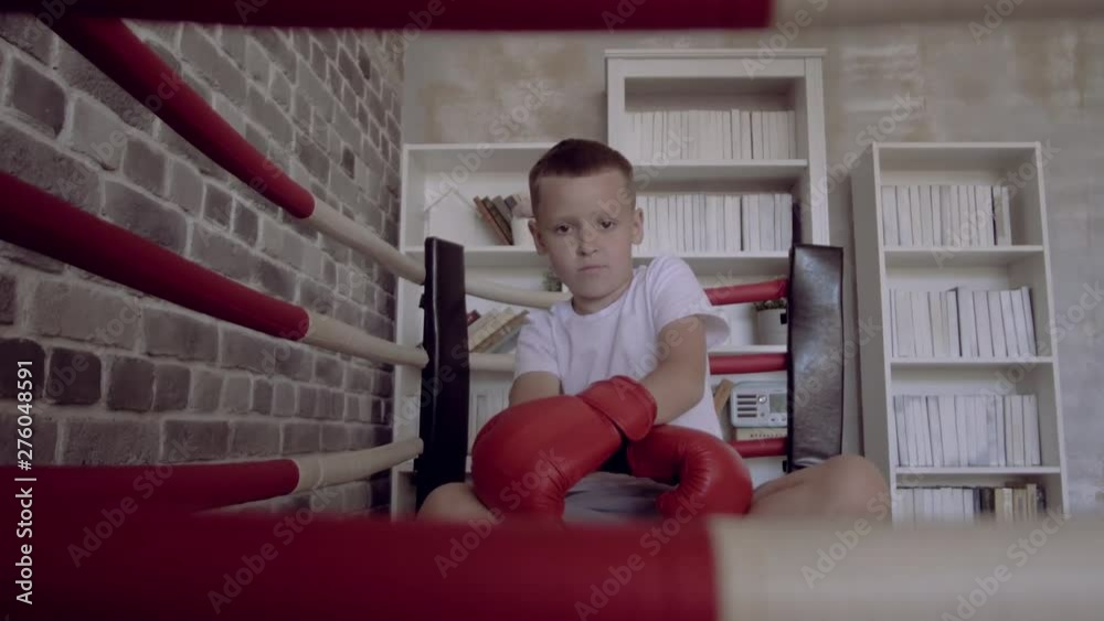Portrait of young boy boxer putting on red boxing gloves in his kid ...