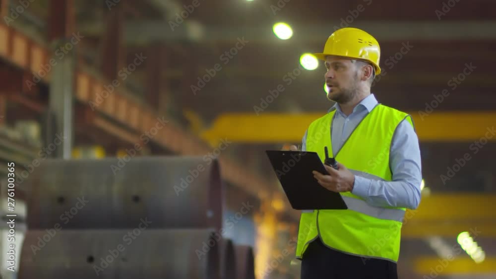 Medium shot of factory unit manager wearing hi-vis neon yellow jacket ...