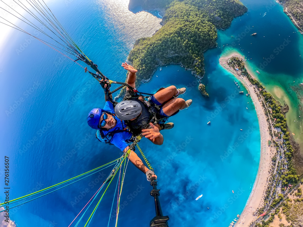 Paragliding in the sky. Paraglider tandem flying over the sea with blue ...