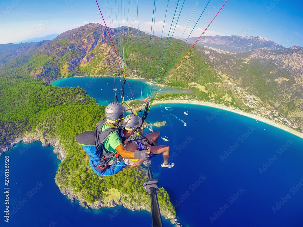 Paragliding in the sky. Paraglider tandem flying over the sea with blue ...