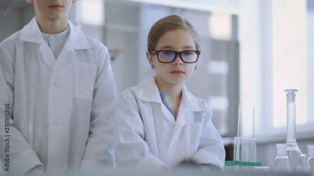 Excited children studying science in a school laboratory watching and ...