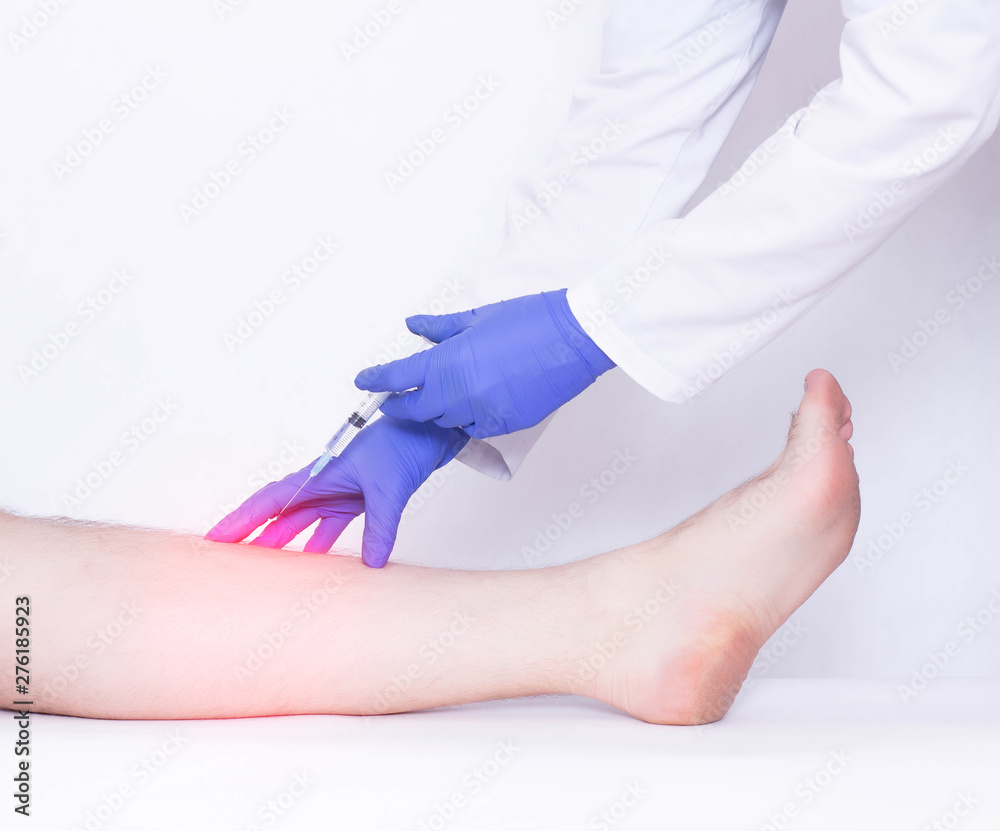 Fotka „The doctor makes an injection into the calf muscle to the ...
