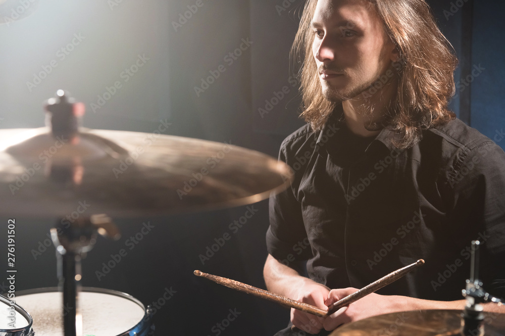 Portrait of a long-haired drummer with chopsticks in his hands sitting ...
