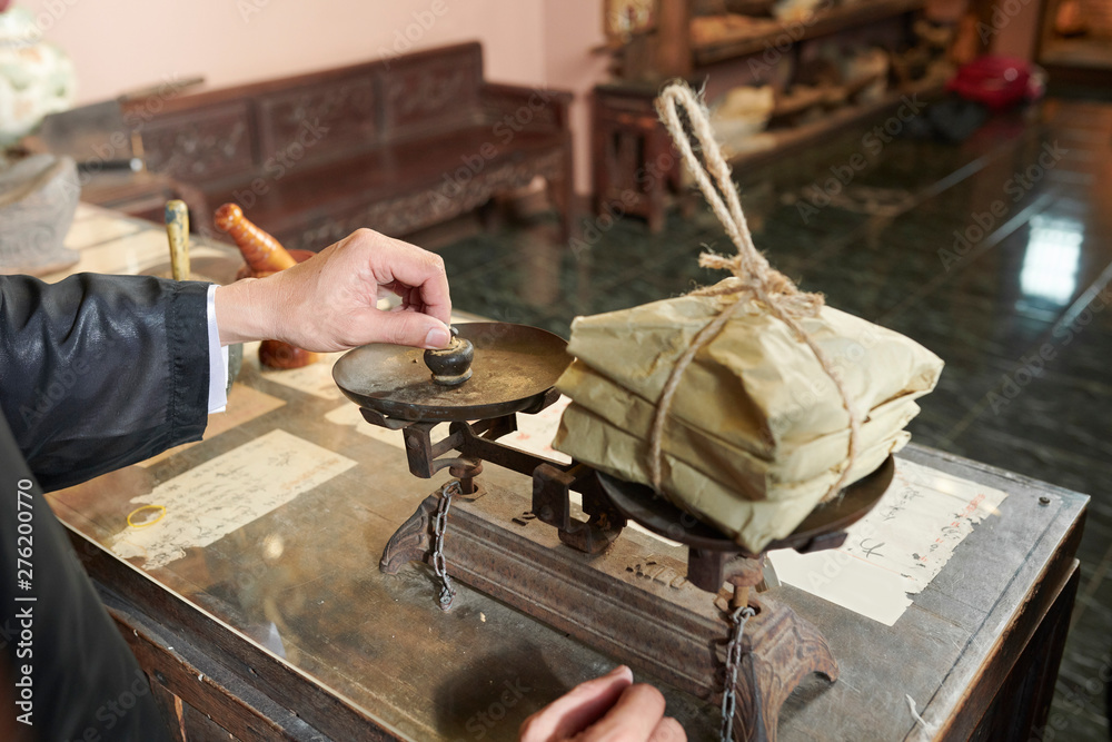 Chinese medicine practitioner using traditional old scales to weight ...