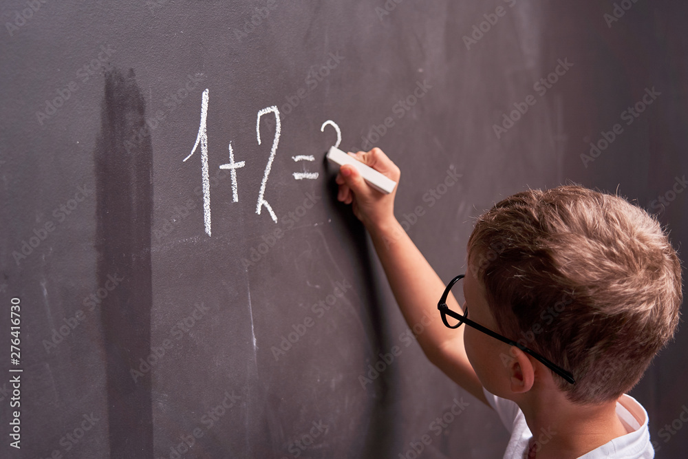 Primary education. Rear view of a schoolboy solves a mathematical ...