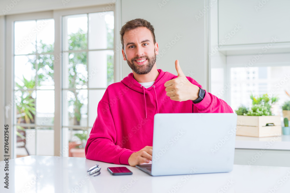 Handsome man working using computer laptop doing happy thumbs up ...