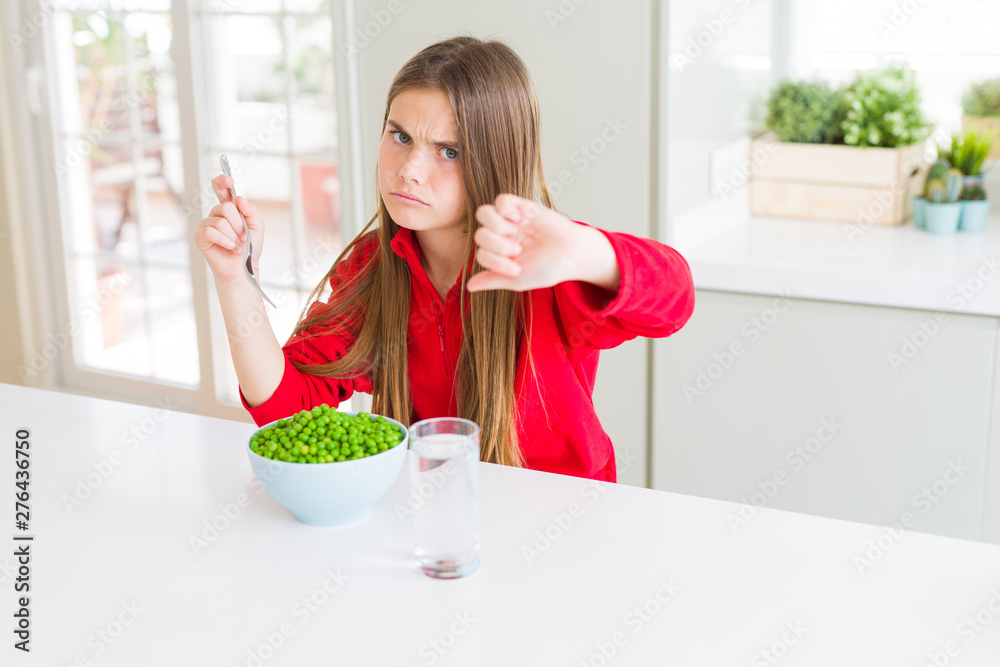 Beautiful young girl eating healthy green peas with angry face ...