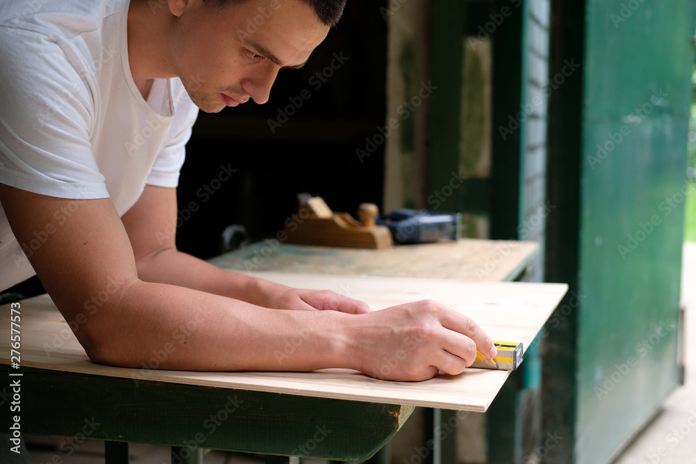 Carpenter marking straight line on plywood sheet using spirit level in ...