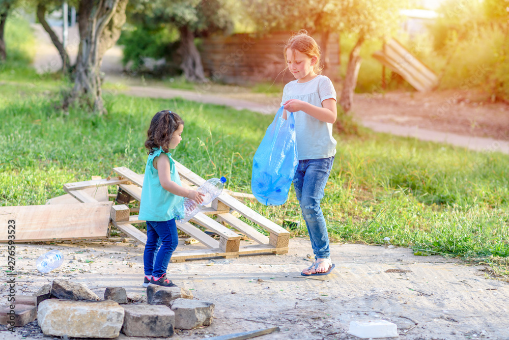 Cute little girls cleaning up plastic litter on grass. Children ...