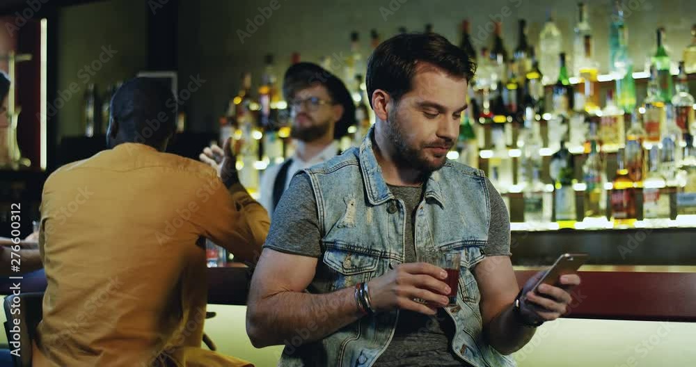 Caucasian young handsome happy man sitting at the bar, drinking an ...
