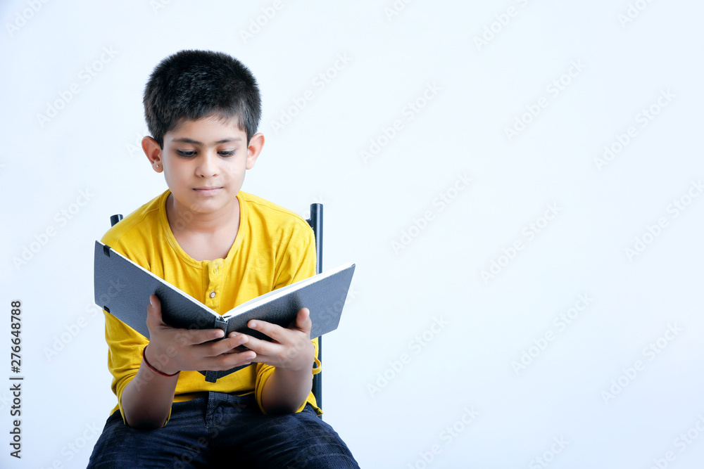 Young indian cute child reading a book Stock Photo | Adobe Stock