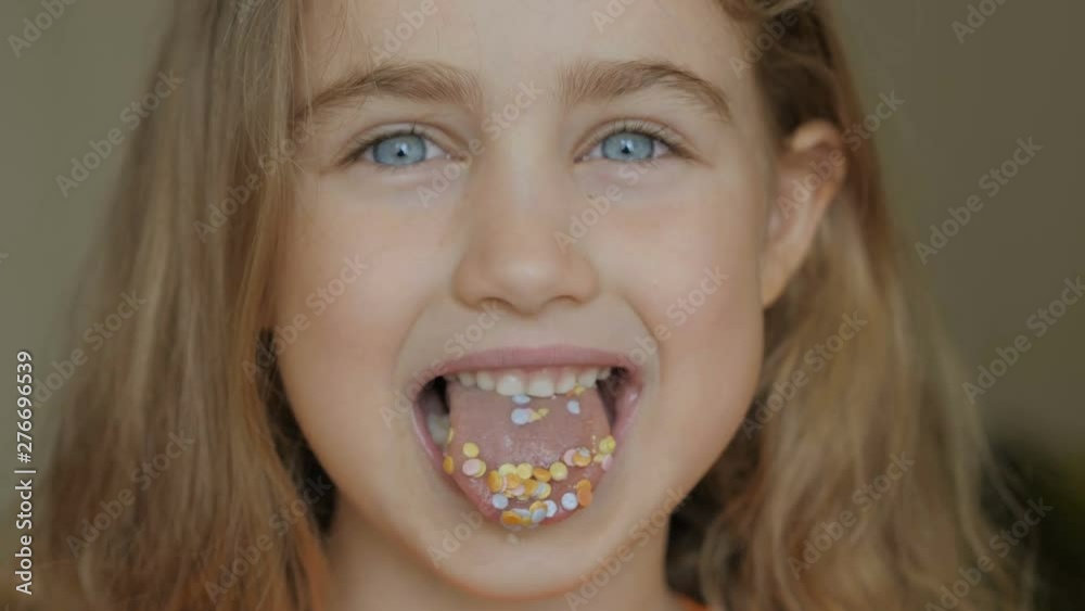A child is smiling with a mouth full of candy. Little girl eating candy ...