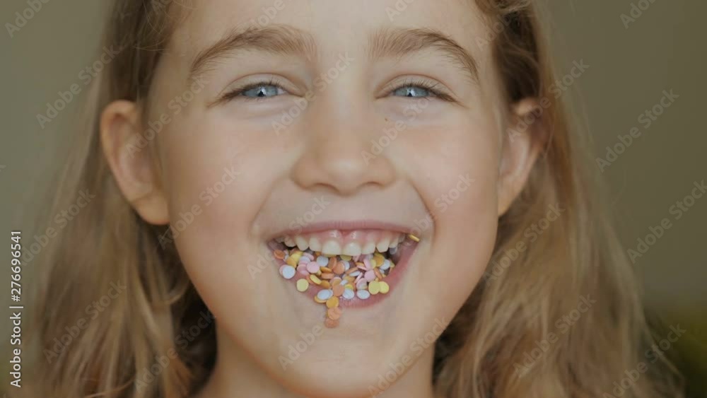 A child is smiling with a mouth full of candy. Little girl eating candy ...