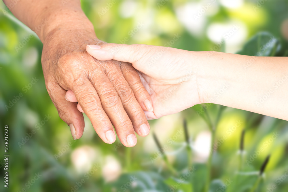 Caregiver, carer hand holding elder hand with blurred nature background ...