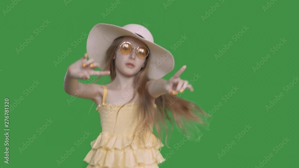 Pre-teen pretty girl in yellow dress and hat is dancing ang singing ...