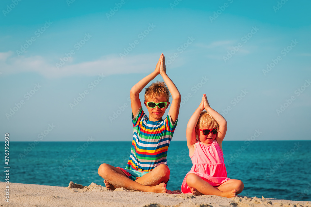 cute boy and little girl doing yoga at beach, kids exercise at sea ...